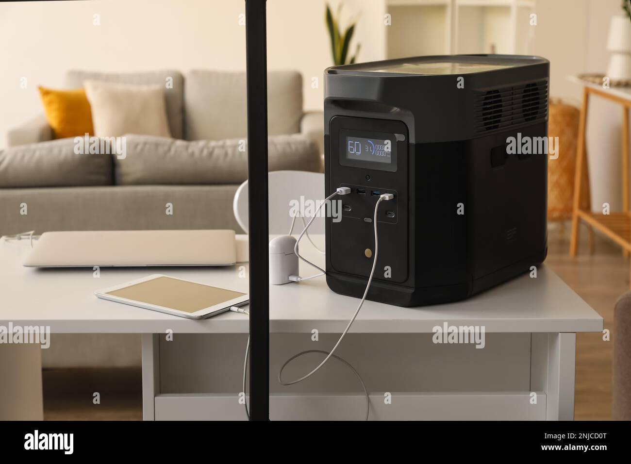 Portable power station charging devices on table in room Stock Photo ...