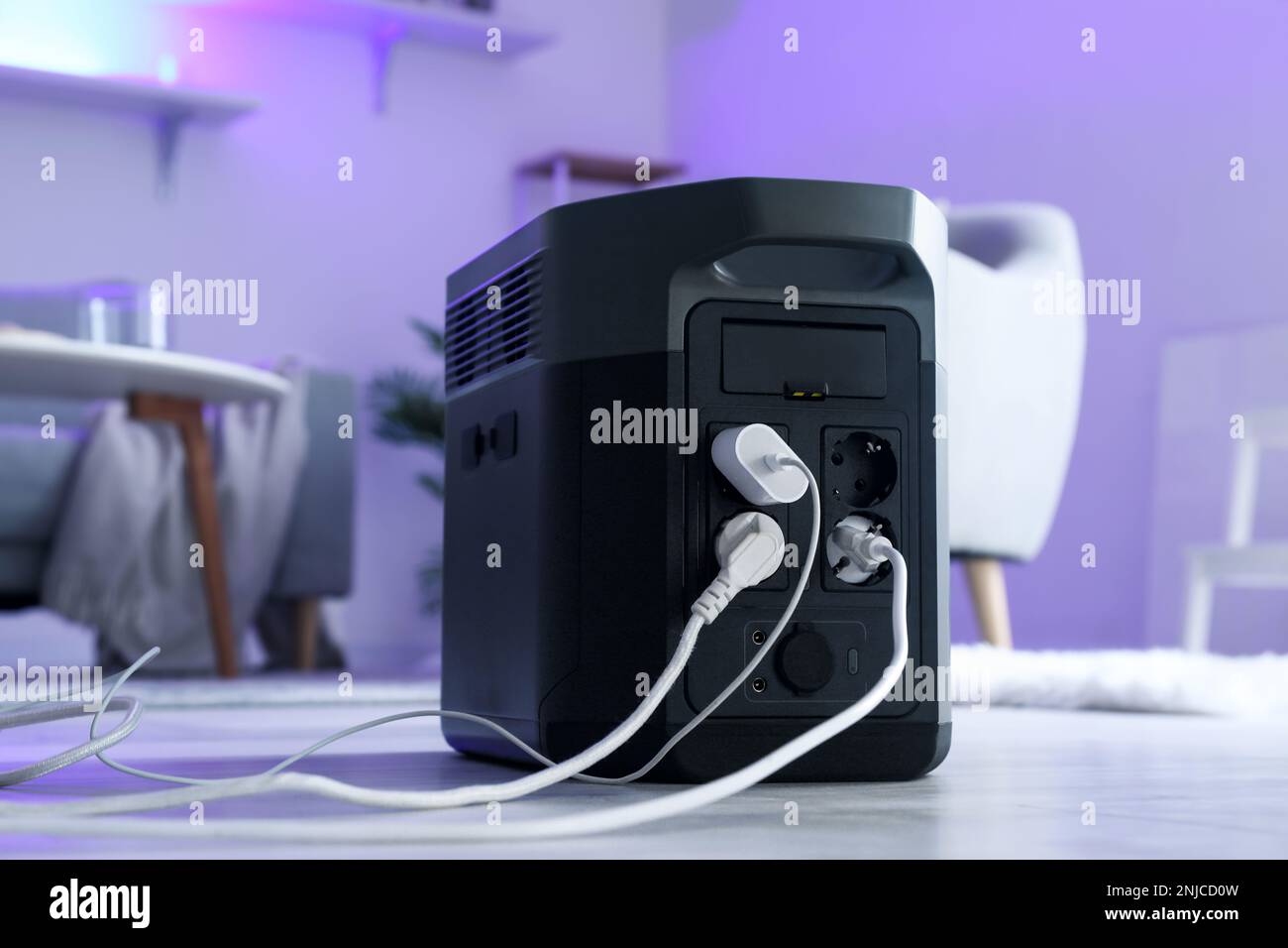 Portable power station charging devices on floor in living room Stock ...