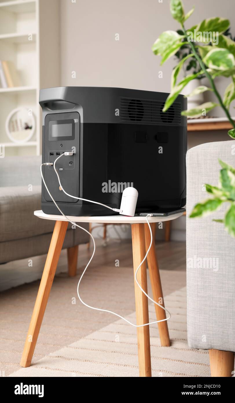 Portable power station charging devices on table in living room Stock ...