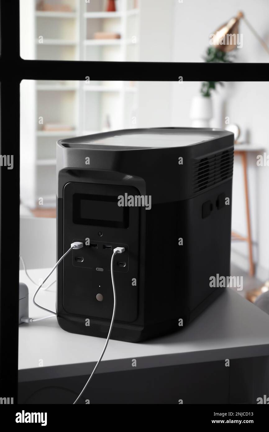 Portable power station charging devices on table in room Stock Photo ...