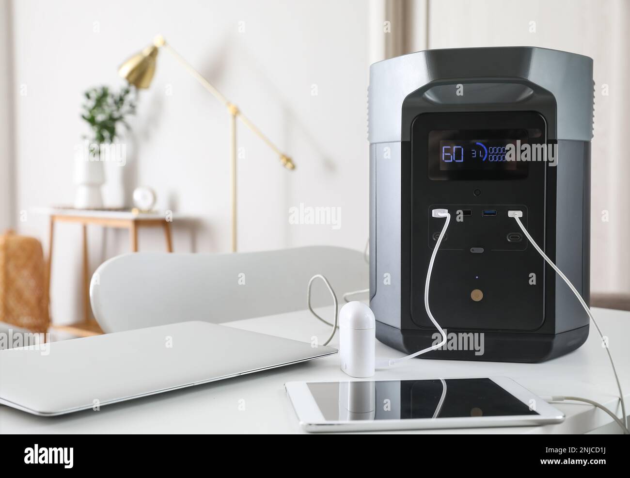 Portable power station charging devices on table in office Stock Photo ...