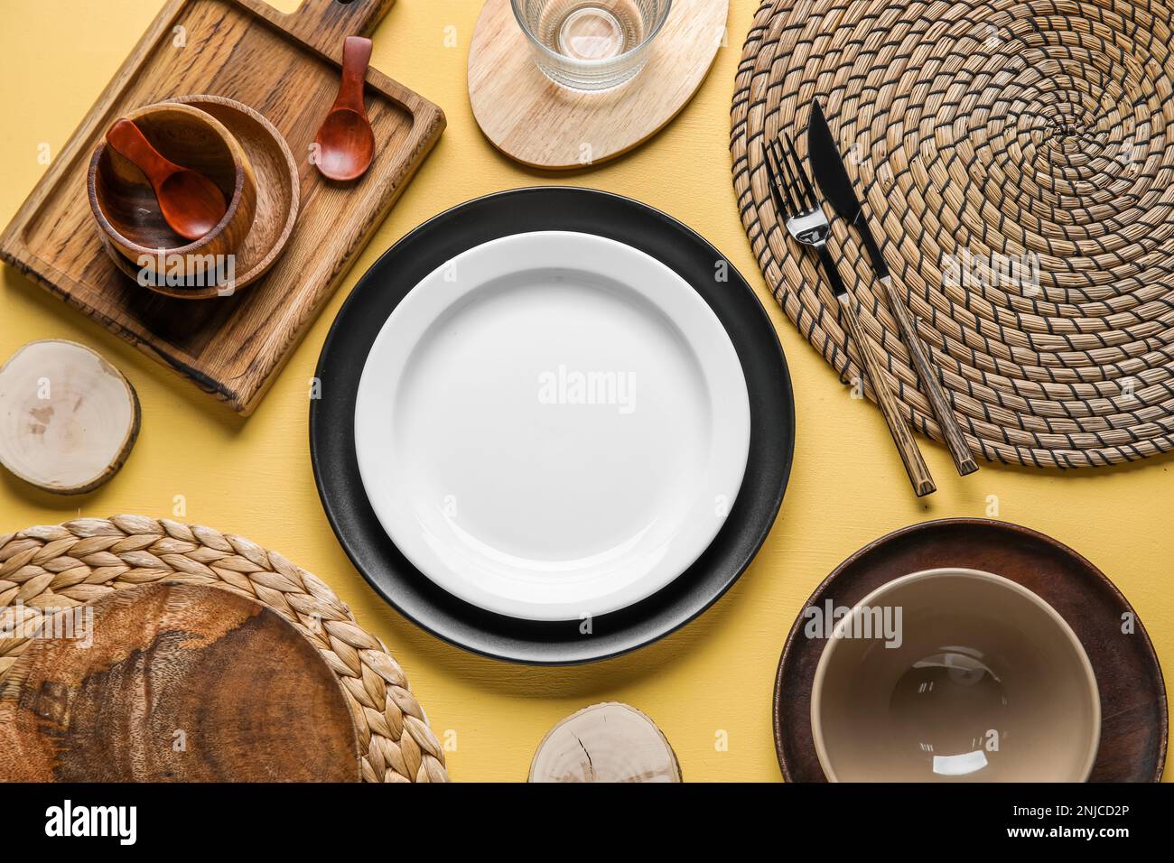 Beautiful table setting with plates, cutlery and wicker mats on yellow ...
