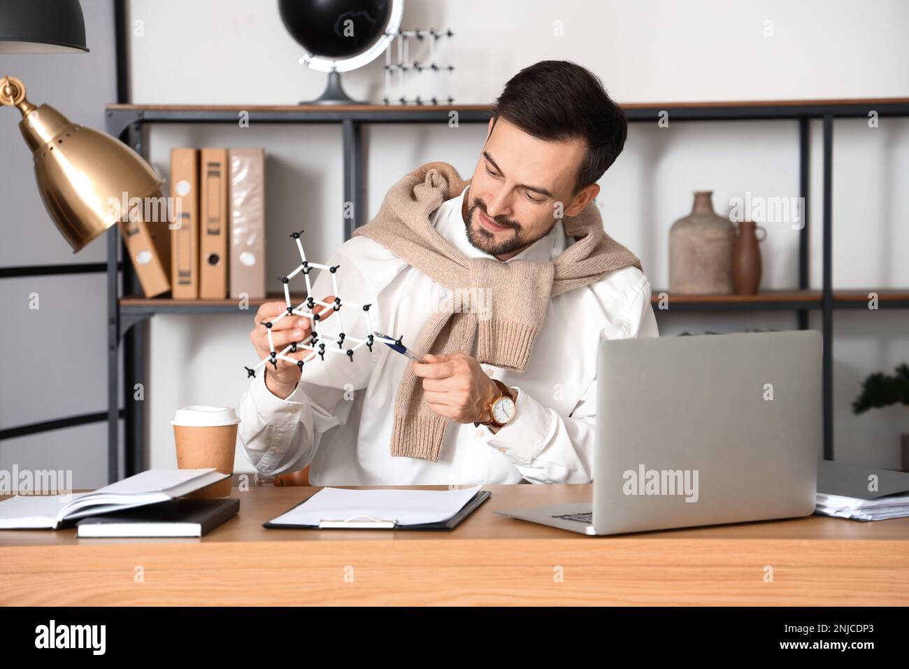 Male tutor with molecular model giving online Physics lesson at home ...