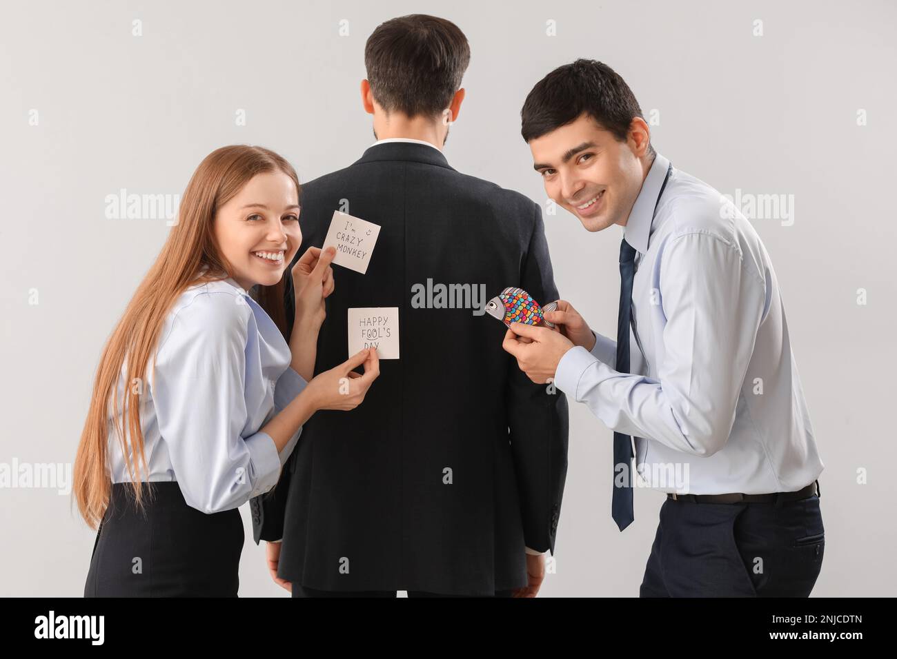 Business people playing a prank on their colleague against light ...