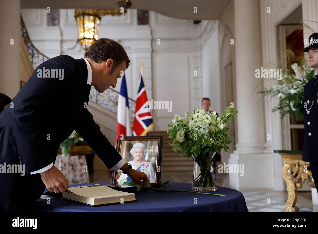 French President Emmanuel Macron places a white rose next to a portrait ...