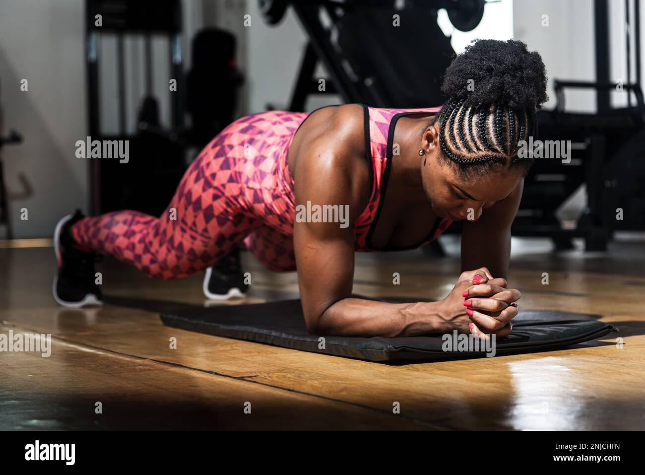 Woman training in modern light studio. Doing a plank with weight on ...
