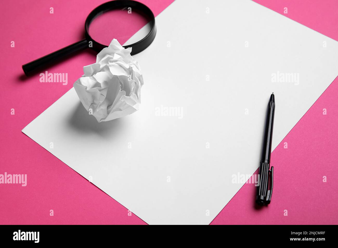 Blank sheet, crumpled paper ball, pen and magnifier on pink background ...