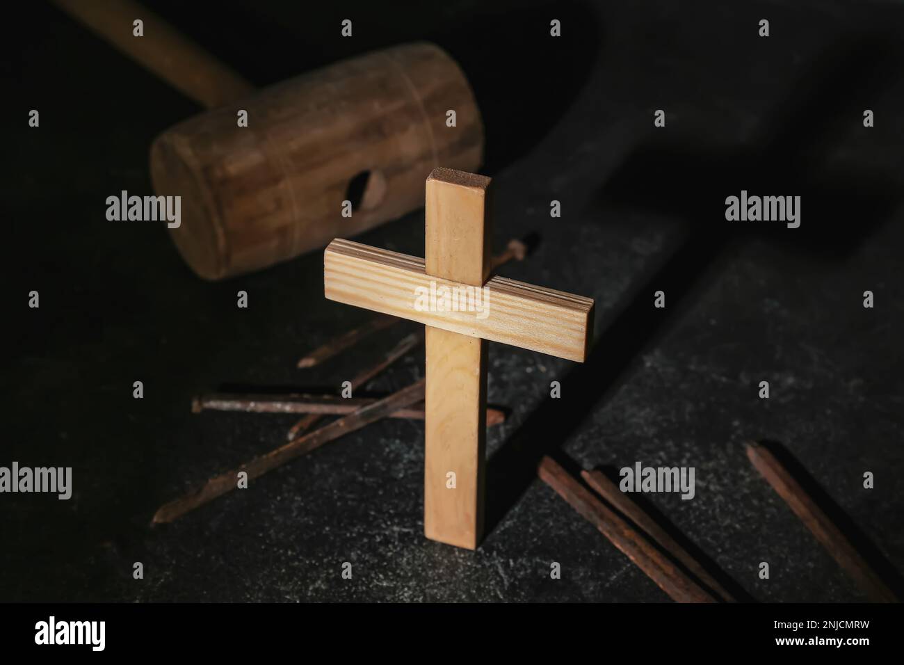 Wooden cross with nails and mallet on dark background, closeup. Good ...