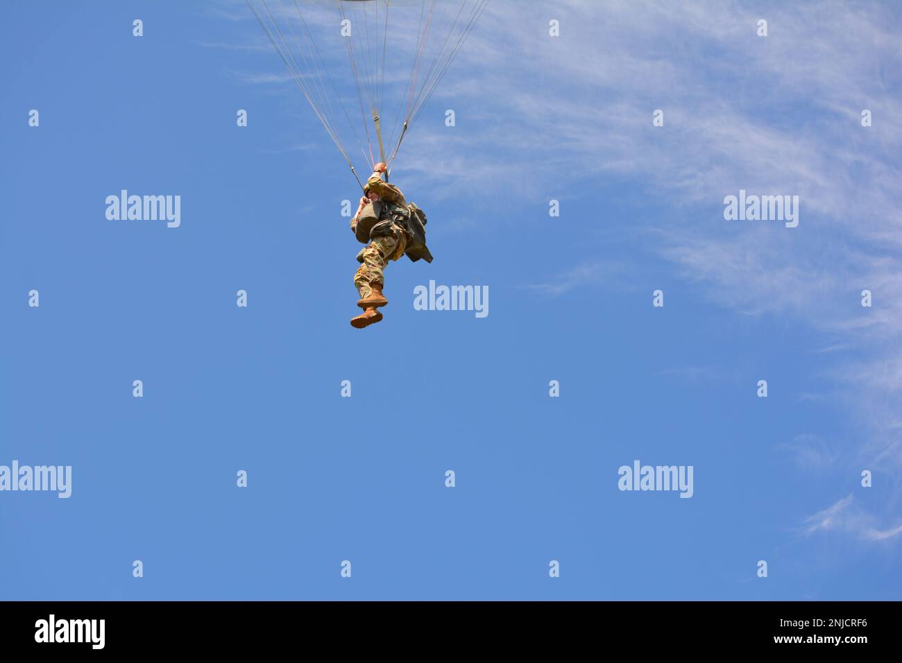 Paratrooper descends with blue sky behind on Glen Rock Drop Zone during ...