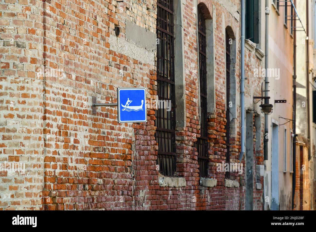 Sign indicating the passage of the gondolas on the wall of a brick ...