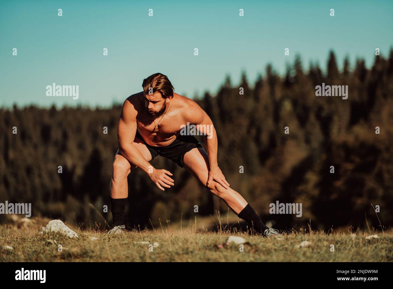 A man stretching after a hard workout in the early hours of the morning ...