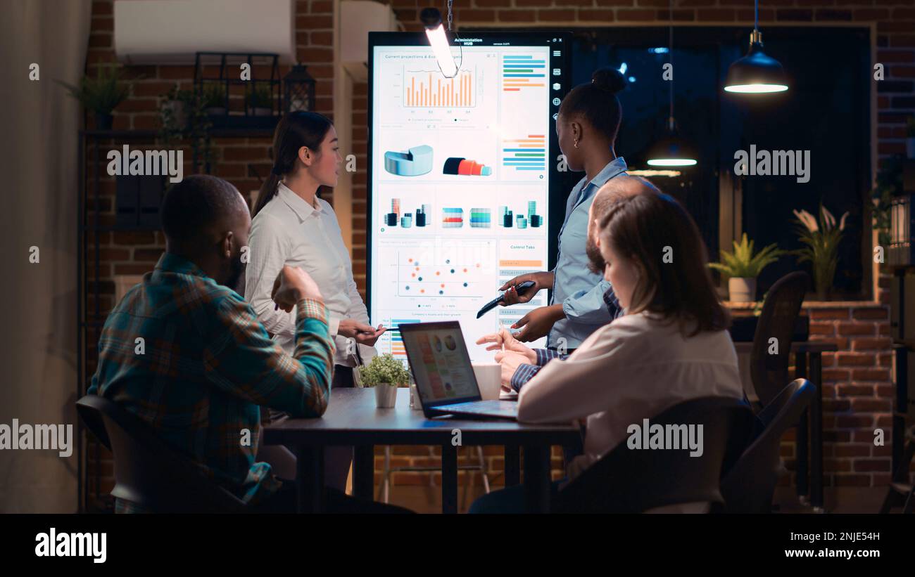 Diverse coworkers presenting analytics report, pointing at data ...