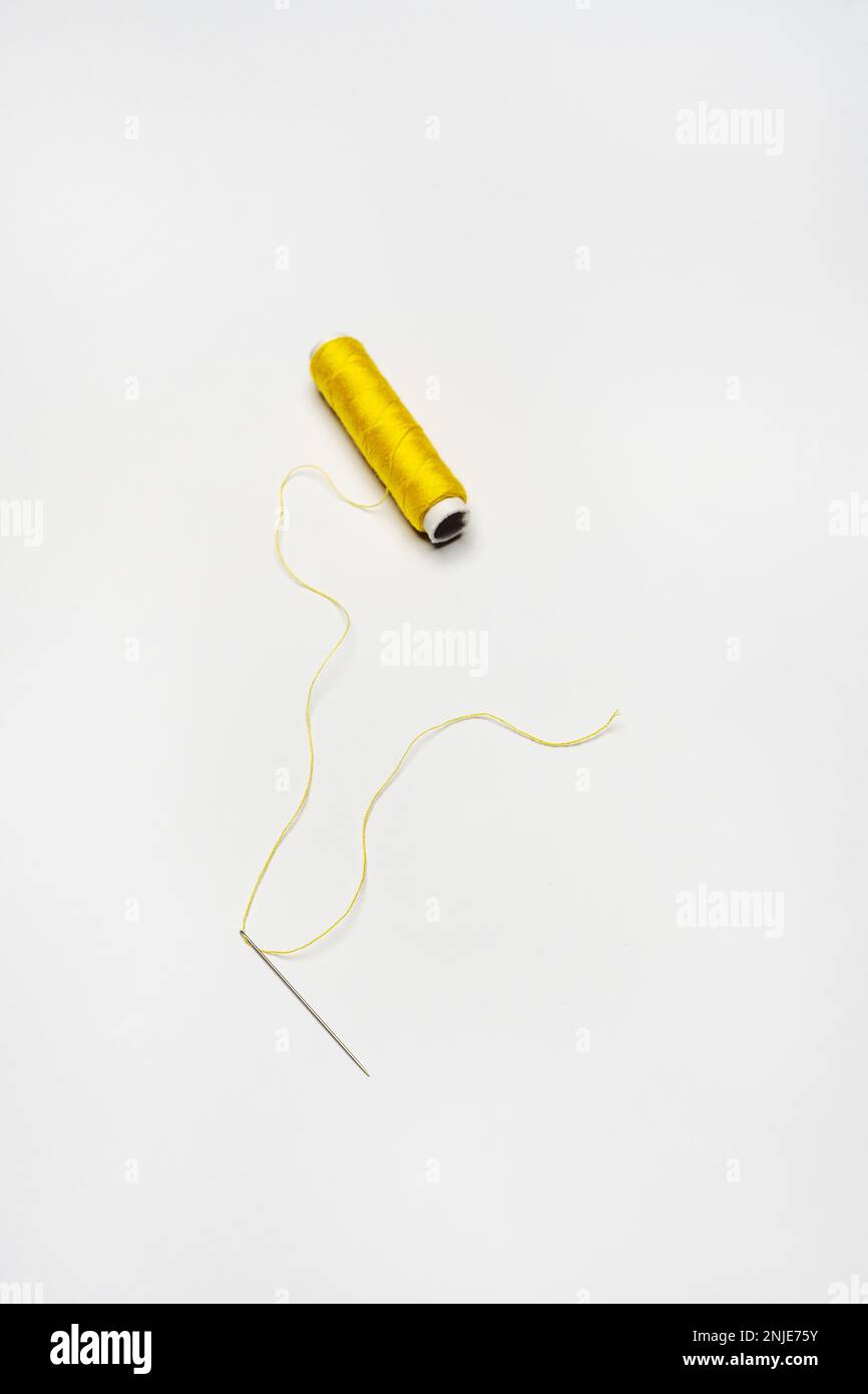 Spools of yellow thread with a needle threaded with thread of the same ...