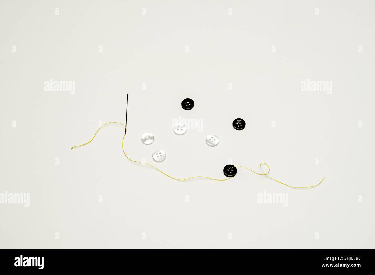 thread of yellow color with a threaded needle, black and white buttons ...
