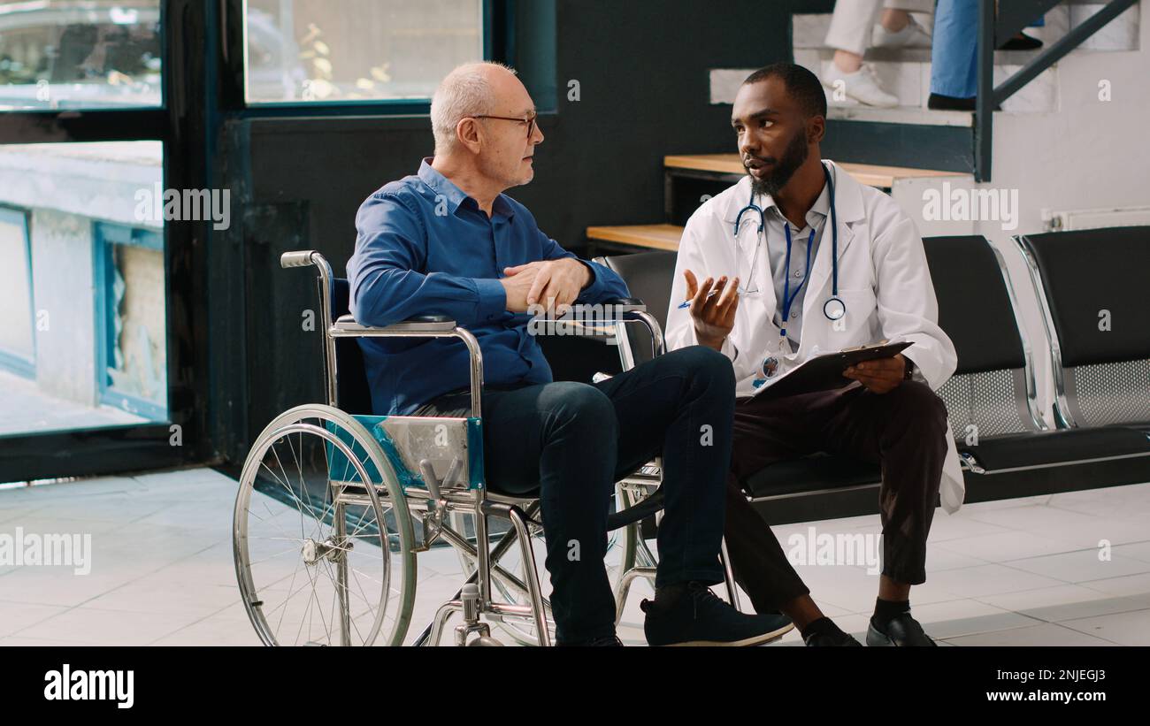 African american doctor doing consultation with old man in wheelchair ...