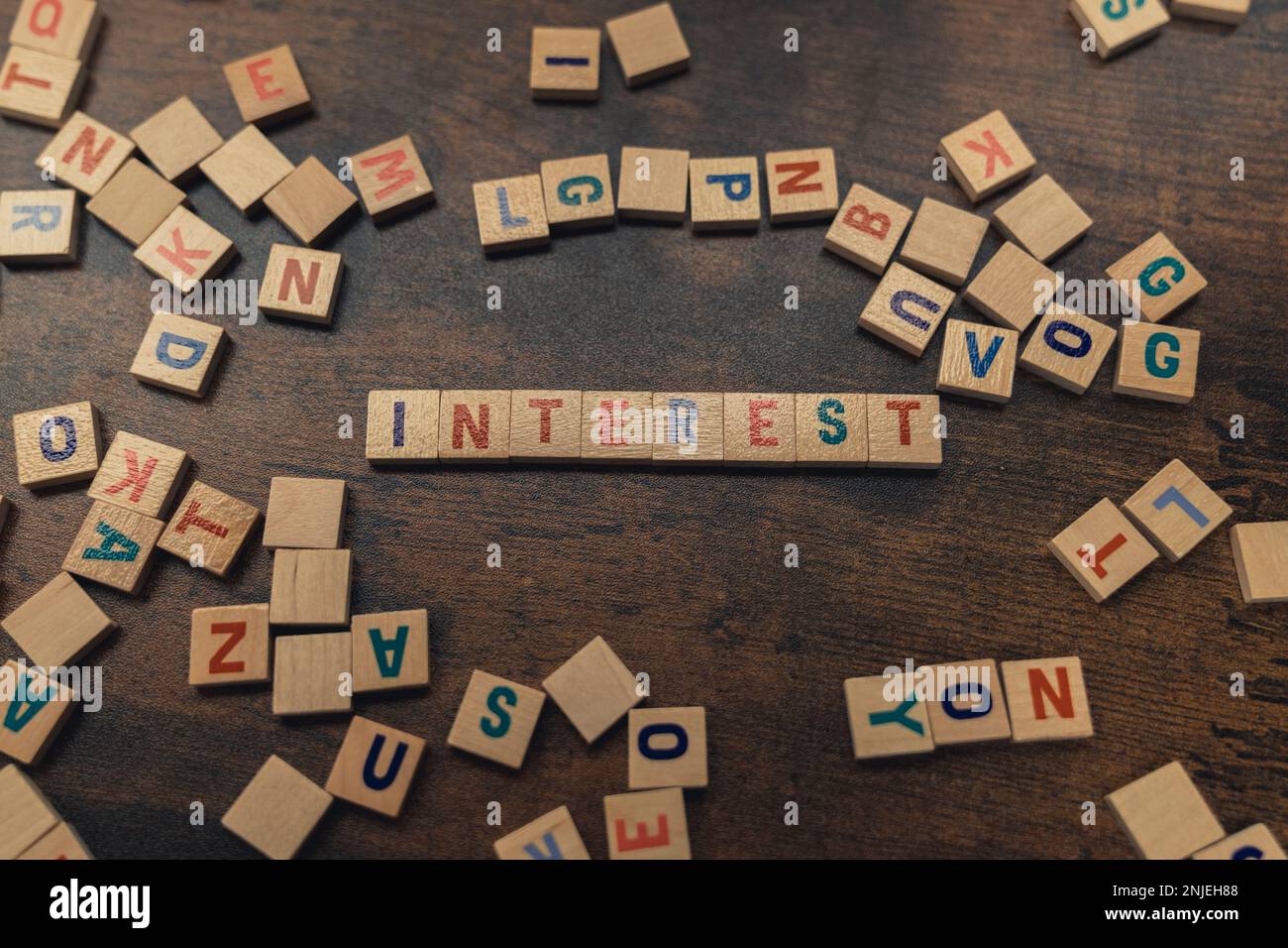 Interest spelled with Scrabble tiles on a brown wooden table alphabets ...