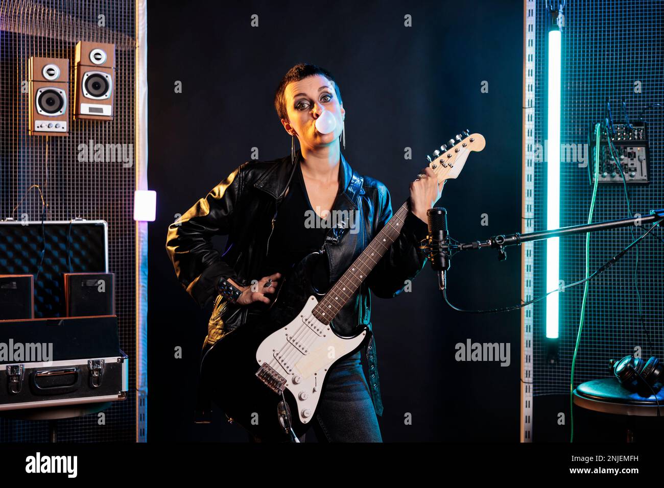 Rock singer blowing bubble gum while posing in studio in isolated ...