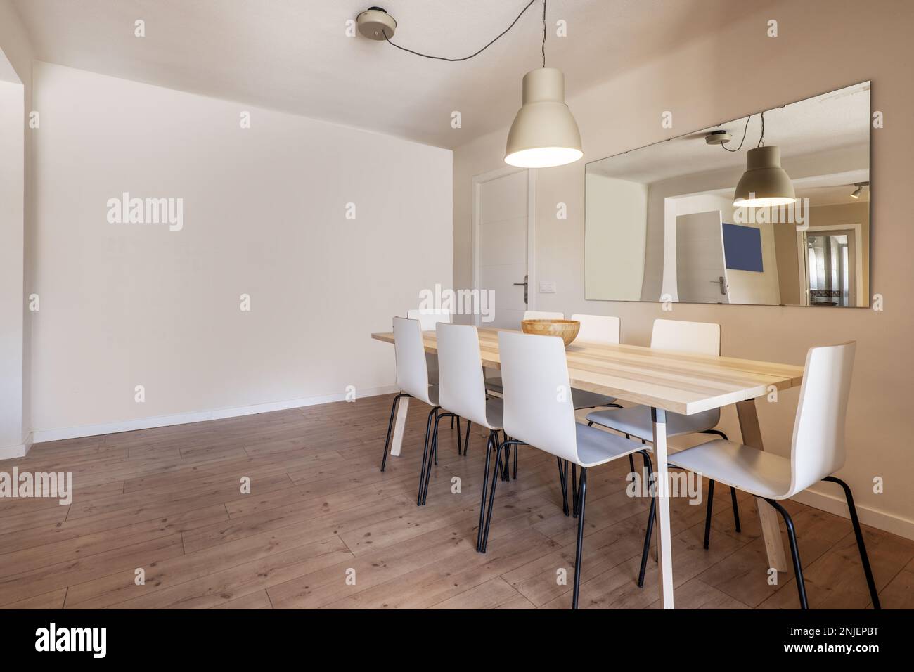 Solid wood dining table next to a mirror in an empty room with chestnut ...