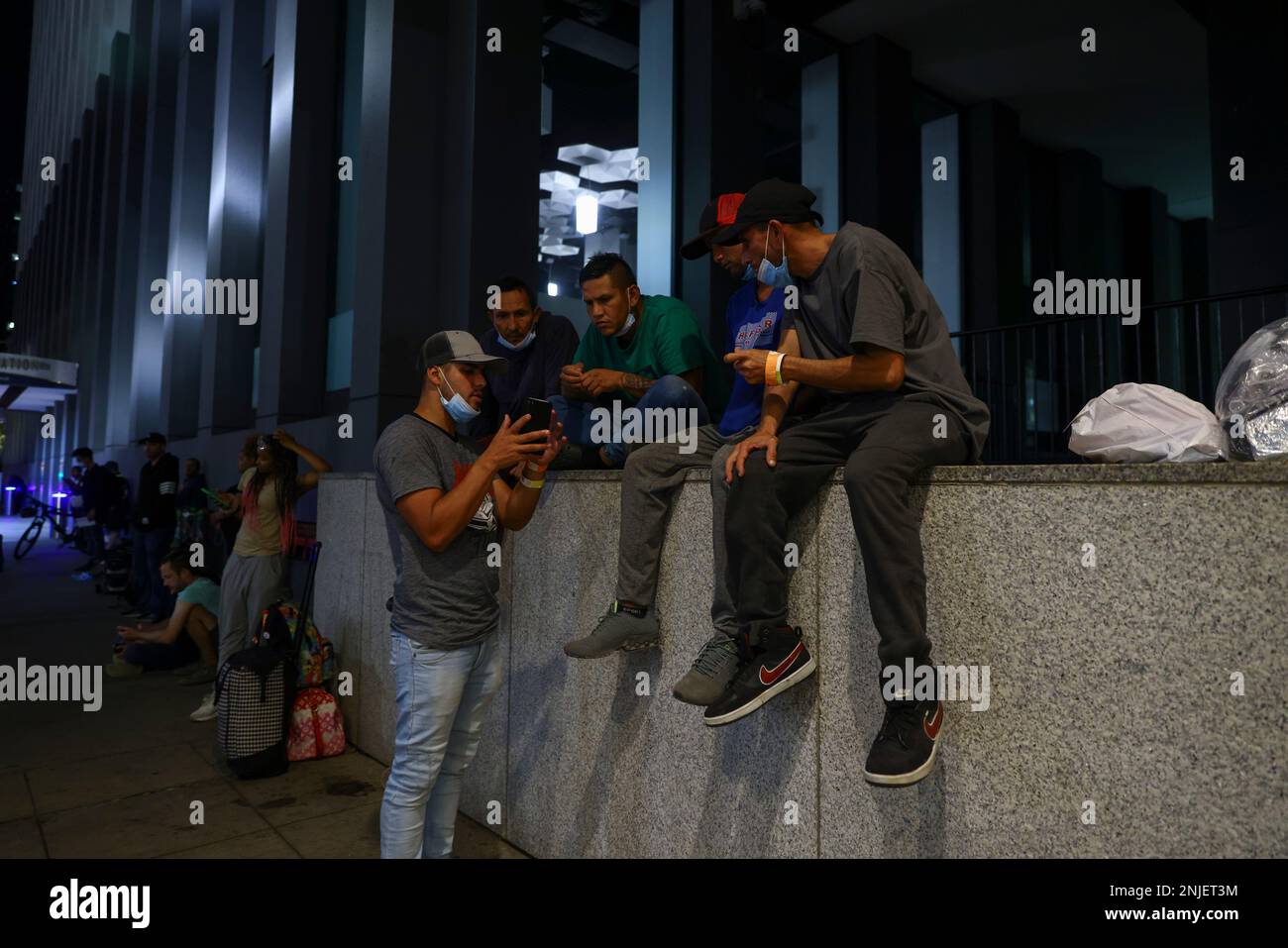 Cesar Rodriguez shares information with other migrants as they wait to ...