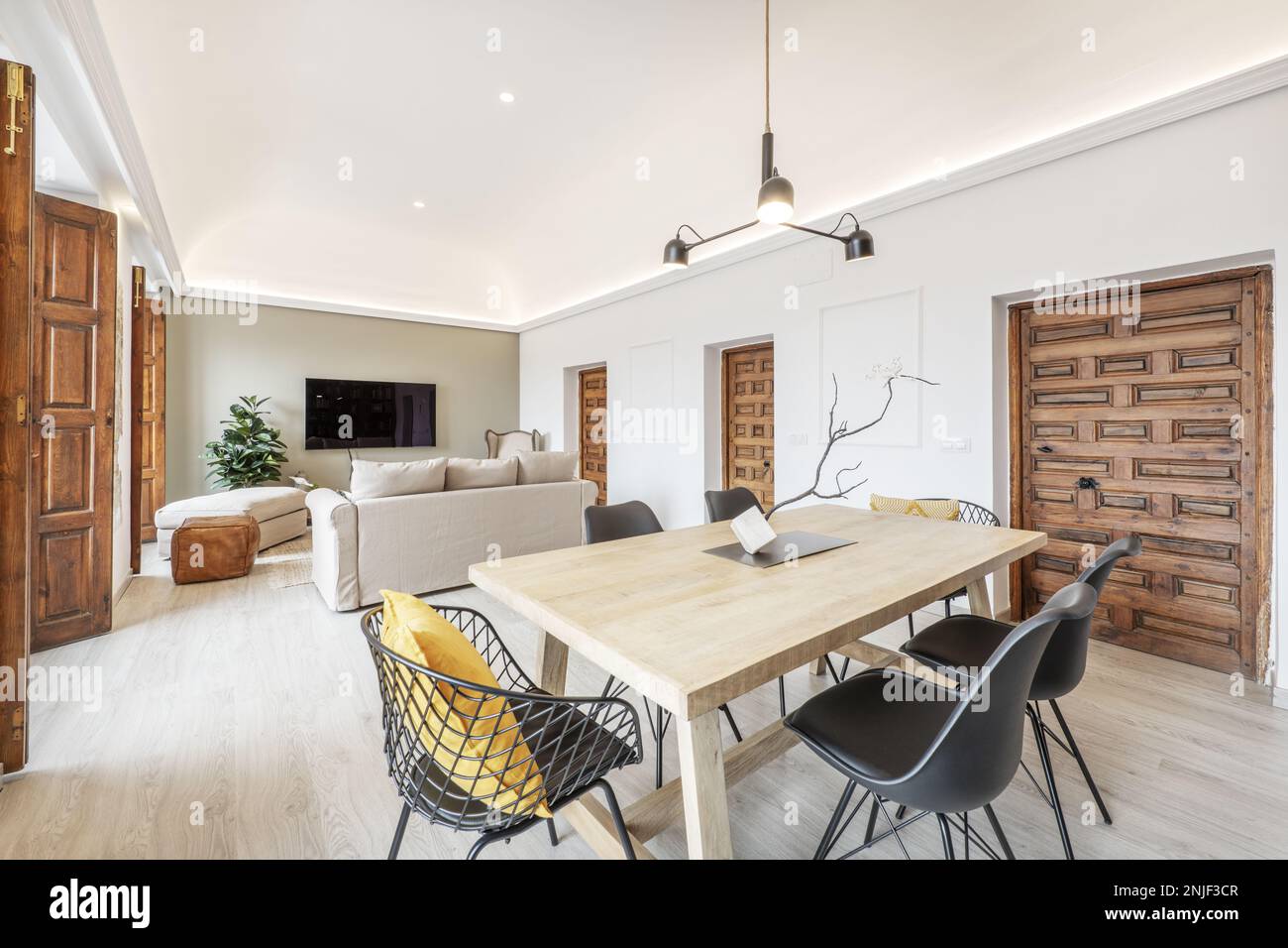 Wooden dining table in a living room with sofas and paneled wooden ...