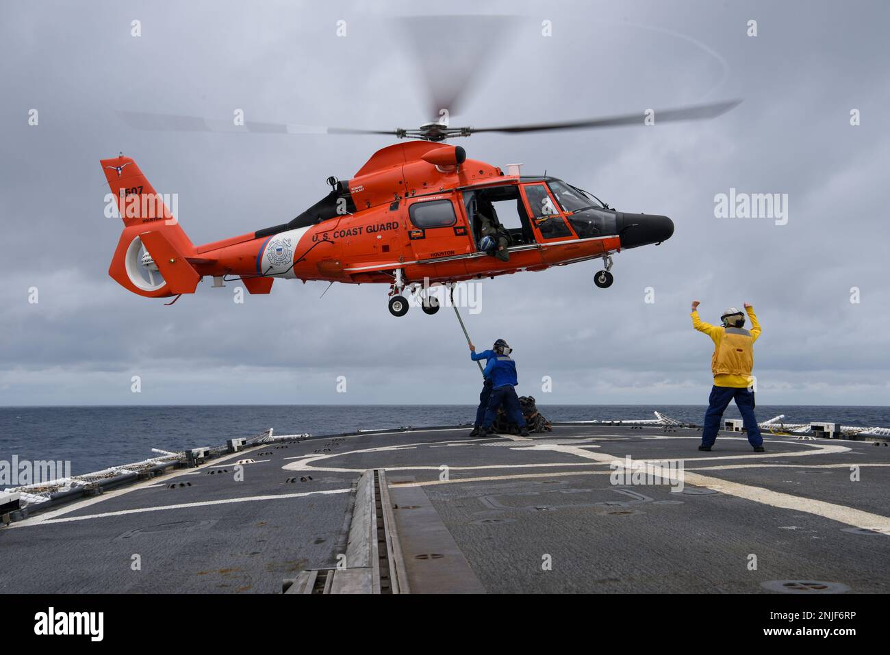 U.S. Coast Guard crewmembers connect the hoisting sling to the ...