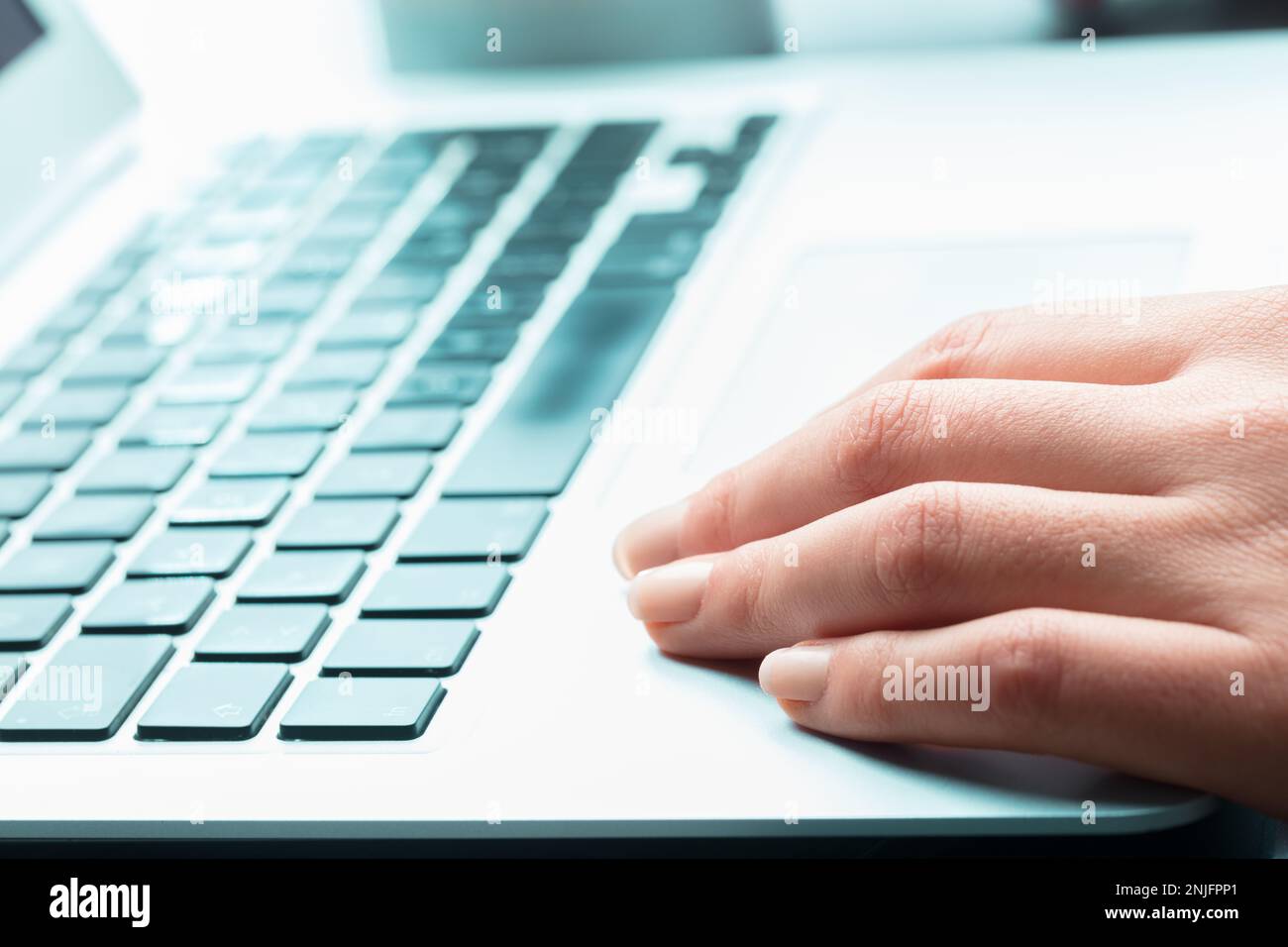 Close-up detail of a manicured female hand resting on a laptop keyboard ...