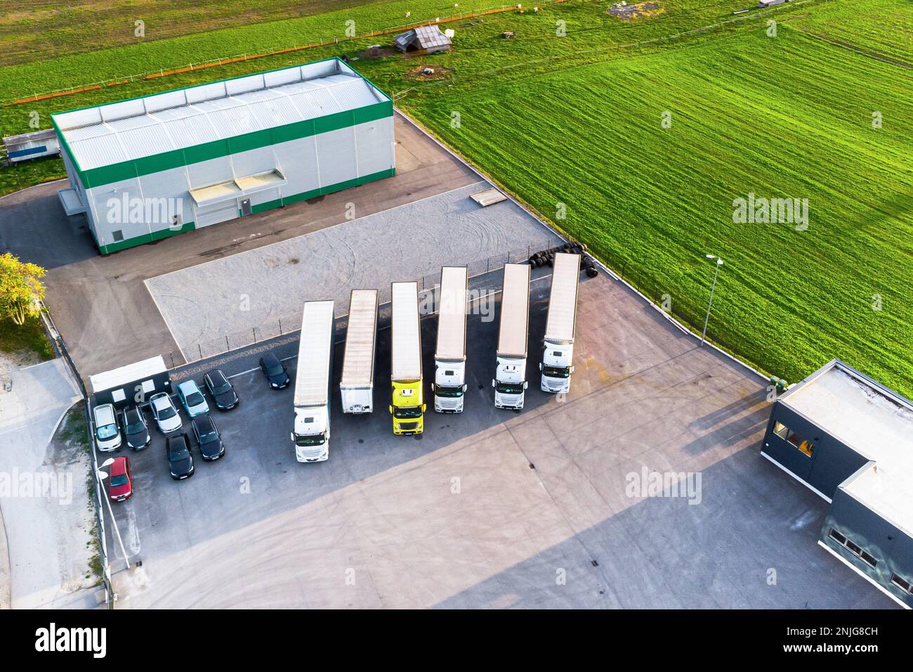 Truck parking lot with six trucks parked in line. Green meadow in the ...