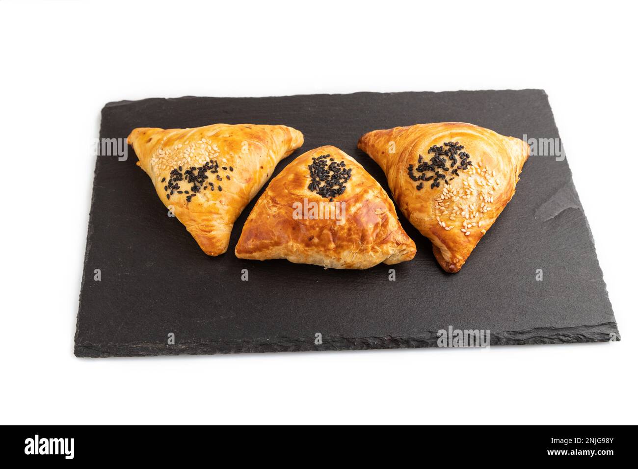 Homemade asian pastry samosa on black slate board isolated on white ...