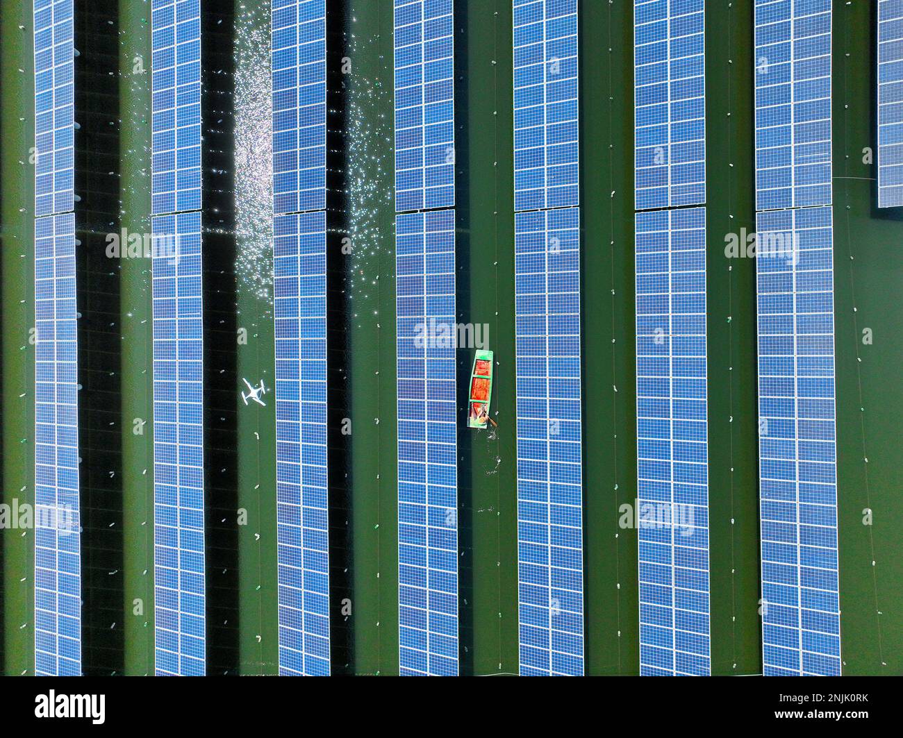 An aerial view of a solar-and-wind power station built over fish ponds ...