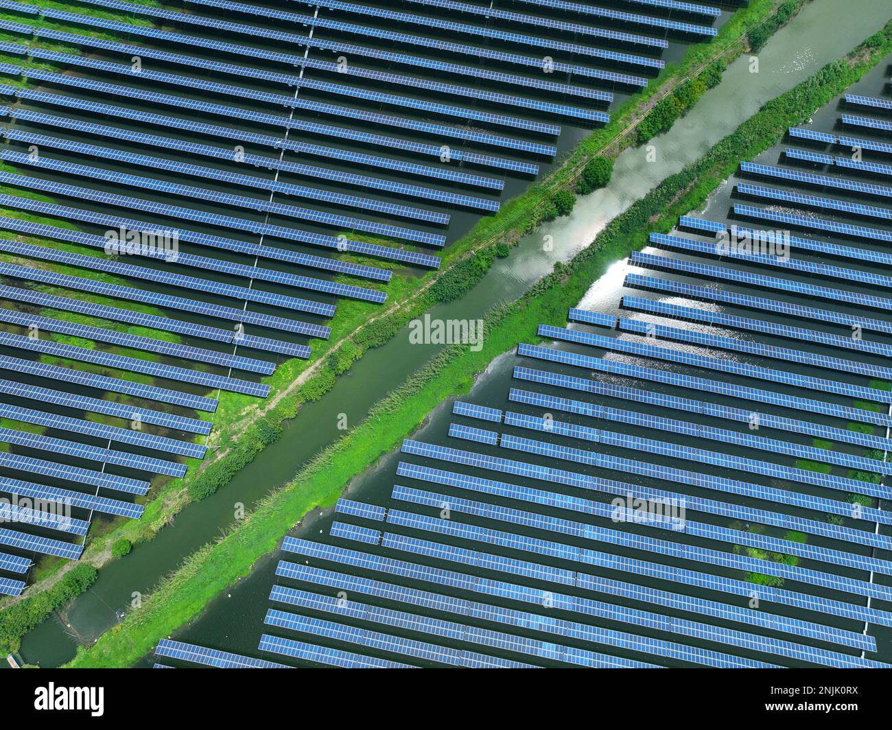 An aerial view of a solar-and-wind power station built over fish ponds ...
