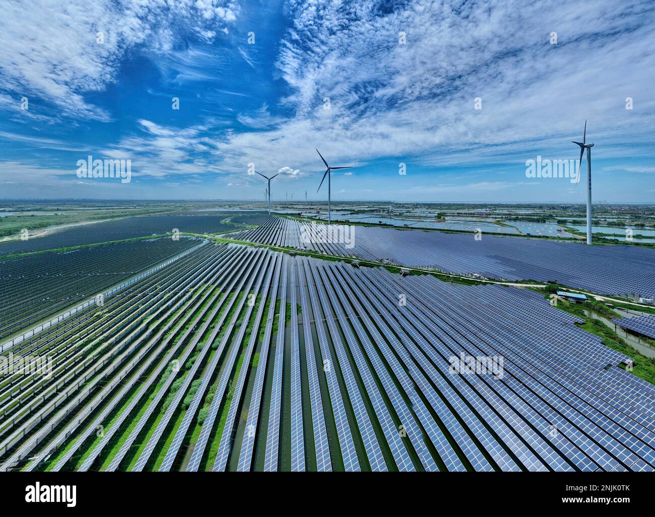 An aerial view of a solar-and-wind power station built over fish ponds ...