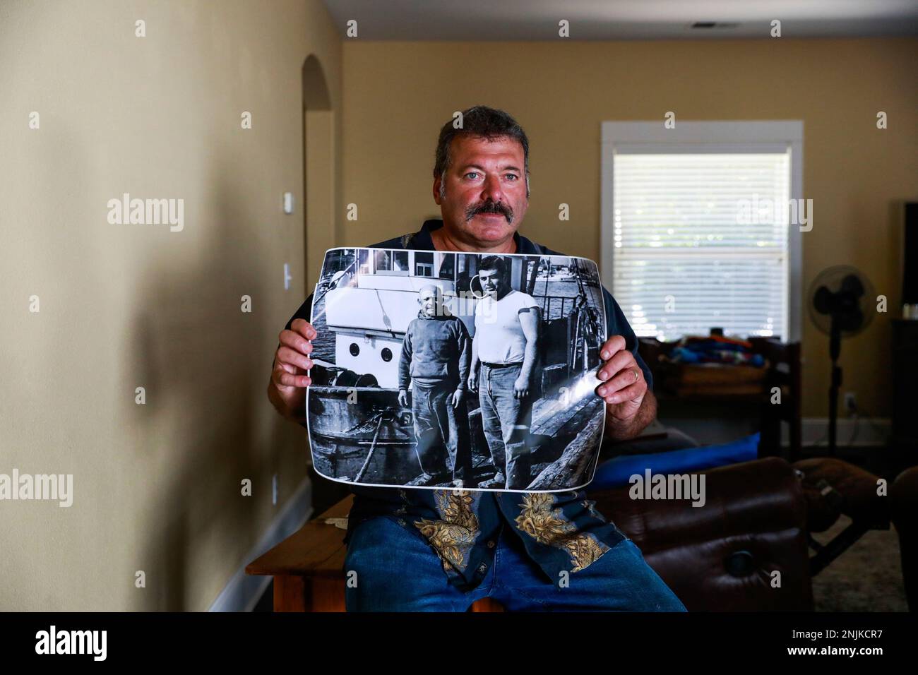 Giuseppe Pennisi shows off a photograph of his grandfather and father ...