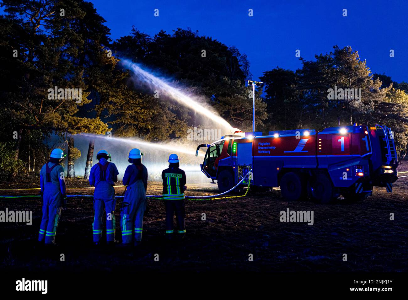 Firefighters use an airfield fire engine to fight a forest fire in the ...