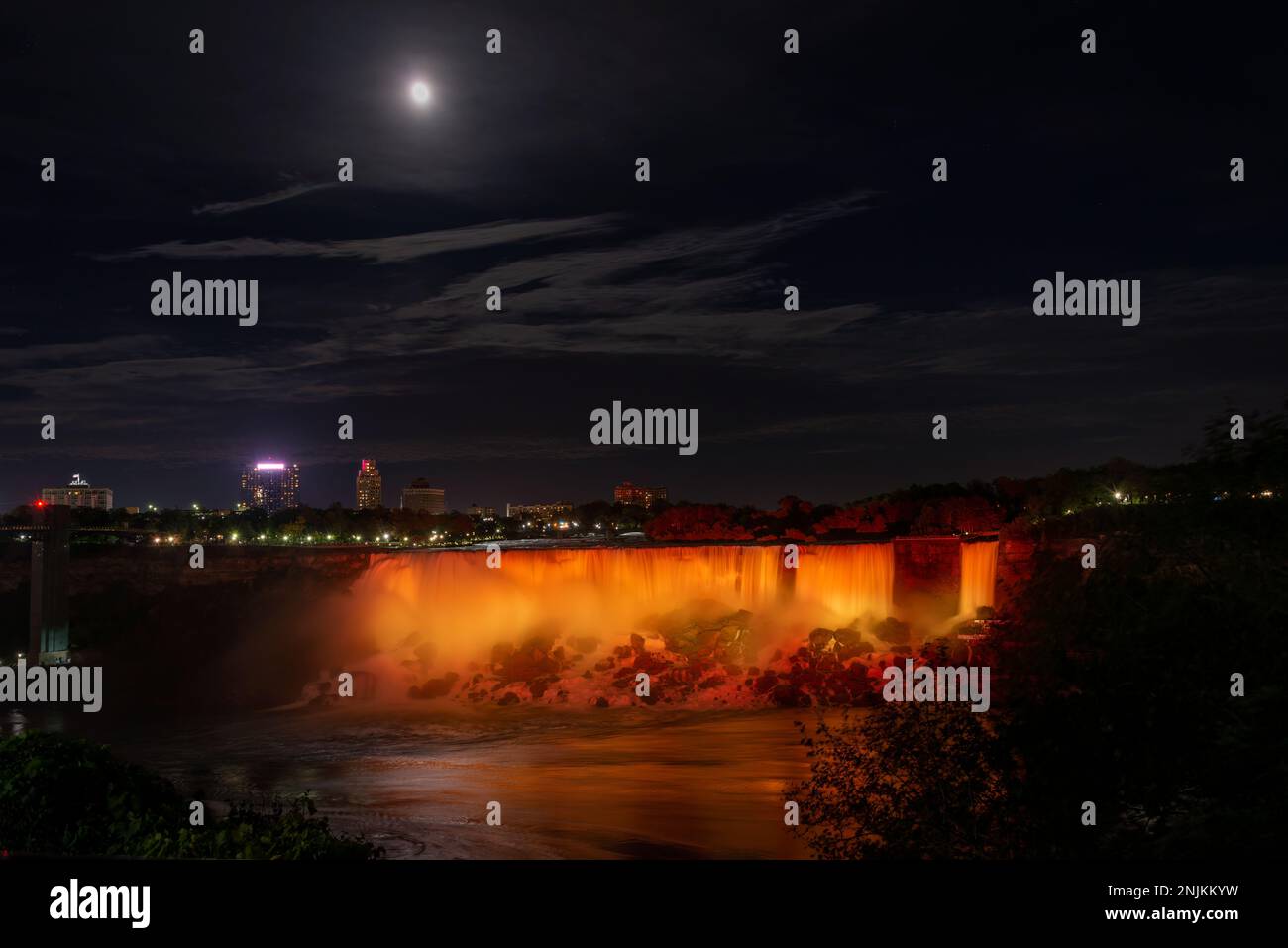 Niagara Falls lit up in gold and yellow under the moonlight. Ontario ...