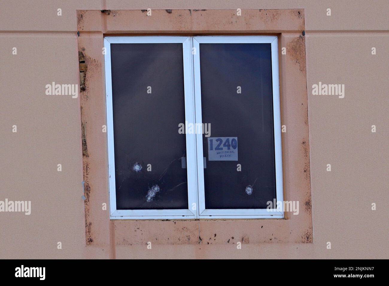 A sign reading "1240 west facing window" and five bullet holes can be ...