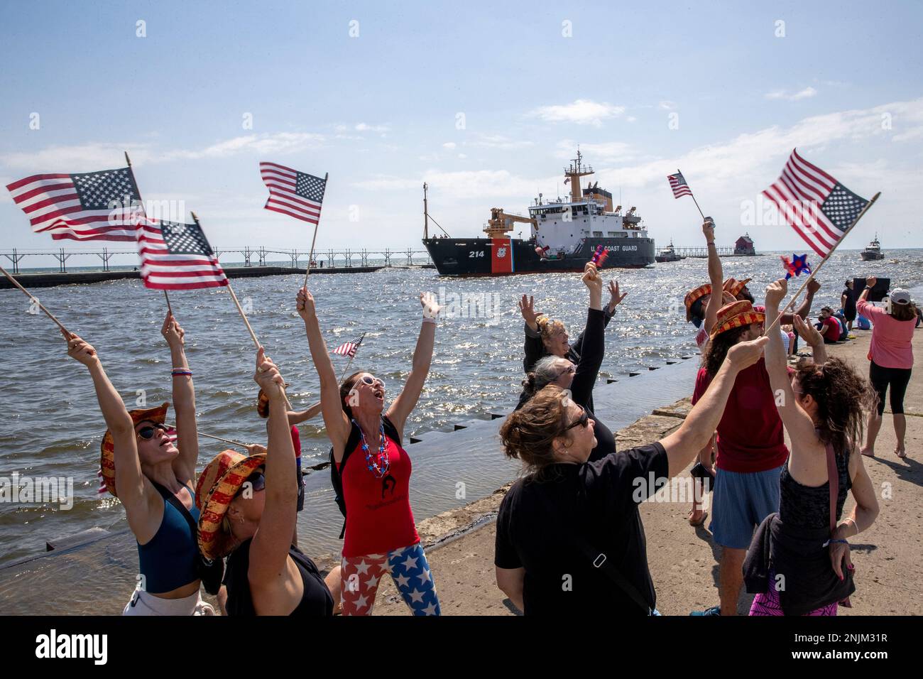 People cheer as a Coast Guard helicopter flies overhead while the USCGC ...
