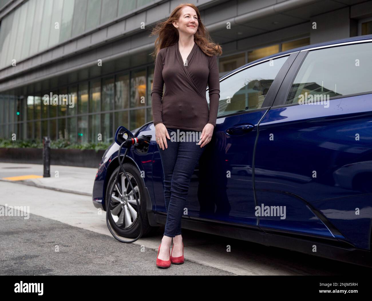 Amy Sinclair poses for a portrait while charging her all-electric ...