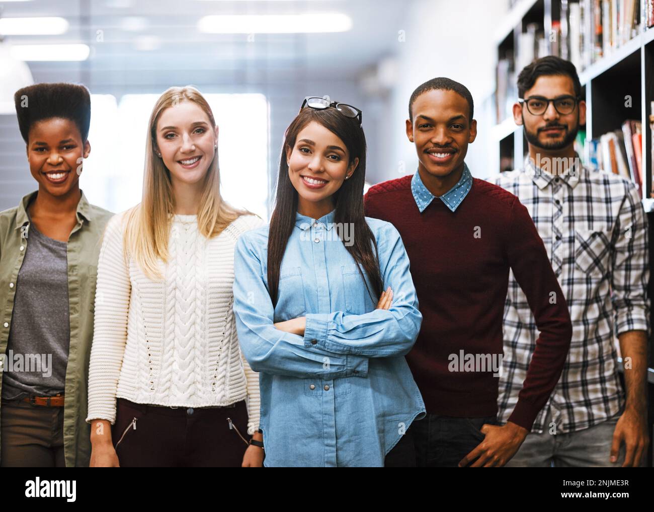 Proud to be a student. university students standing in the library on ...