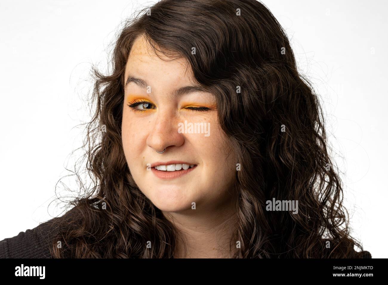Close up portrait of pretty young woman winking at the camera on white ...