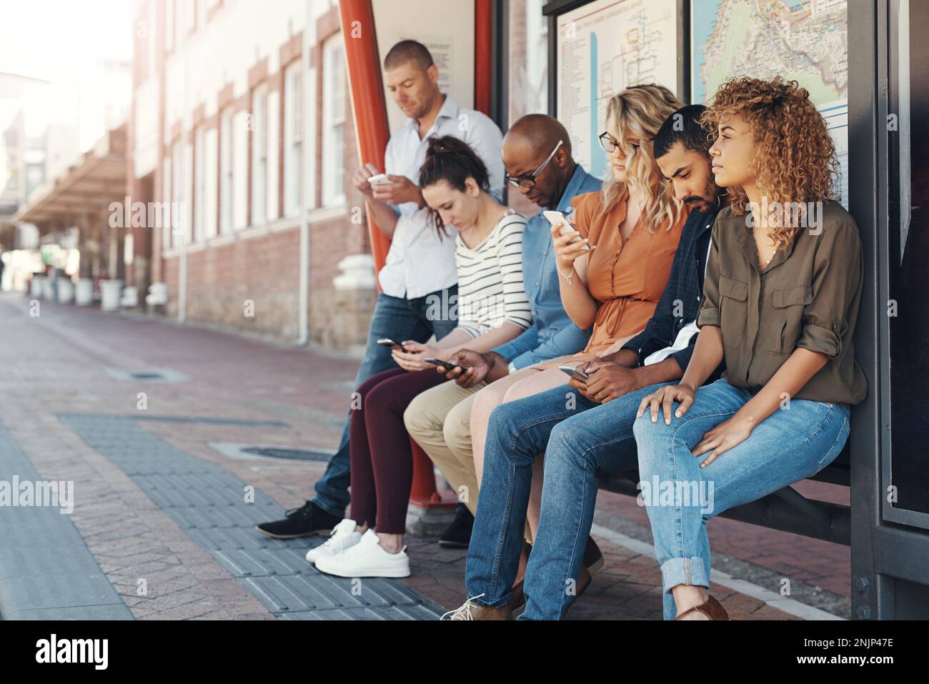 Young man using mobile phone at bus stop hi-res stock photography and ...