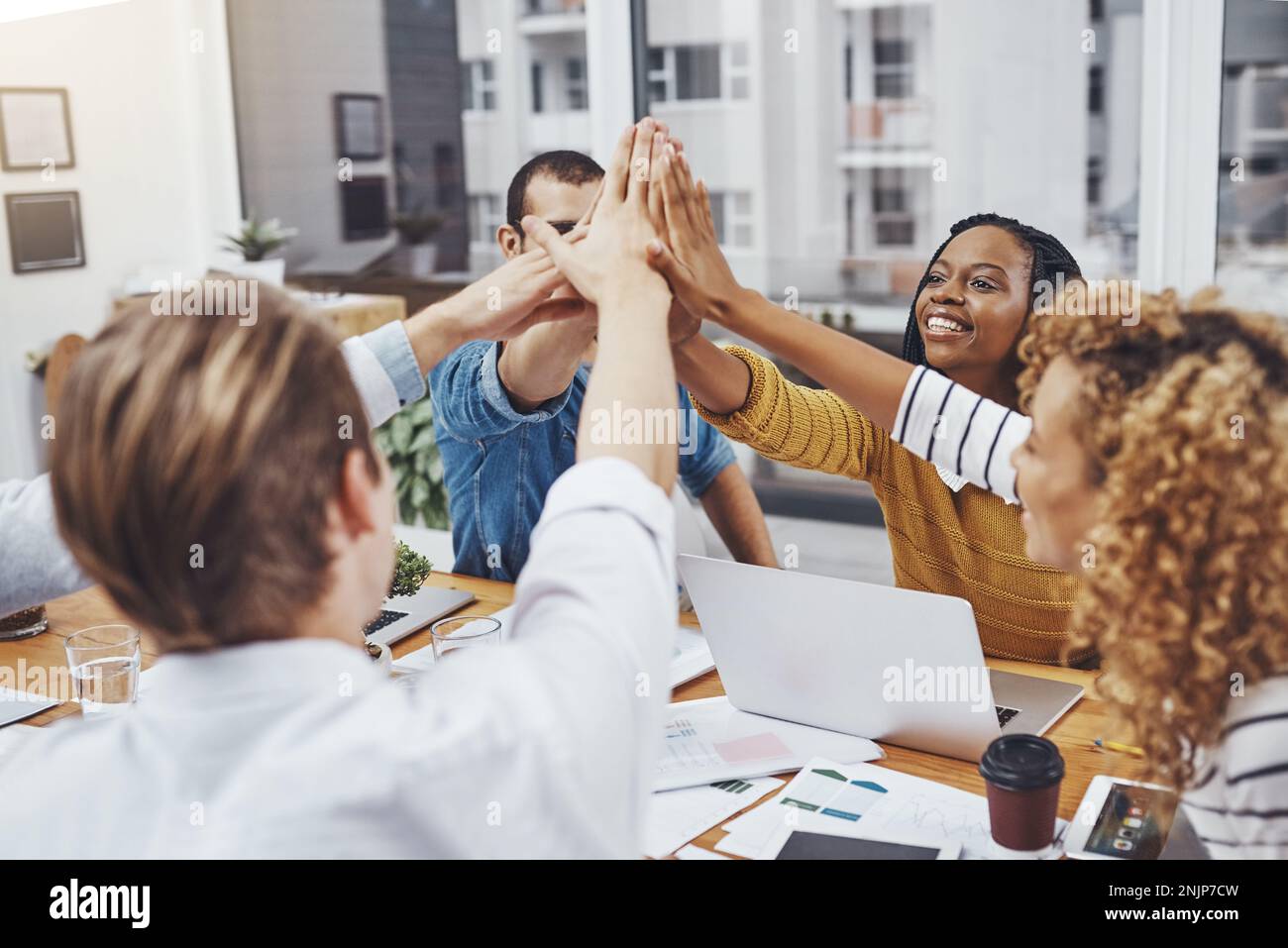 Go team. colleagues high-fiving in the office Stock Photo - Alamy