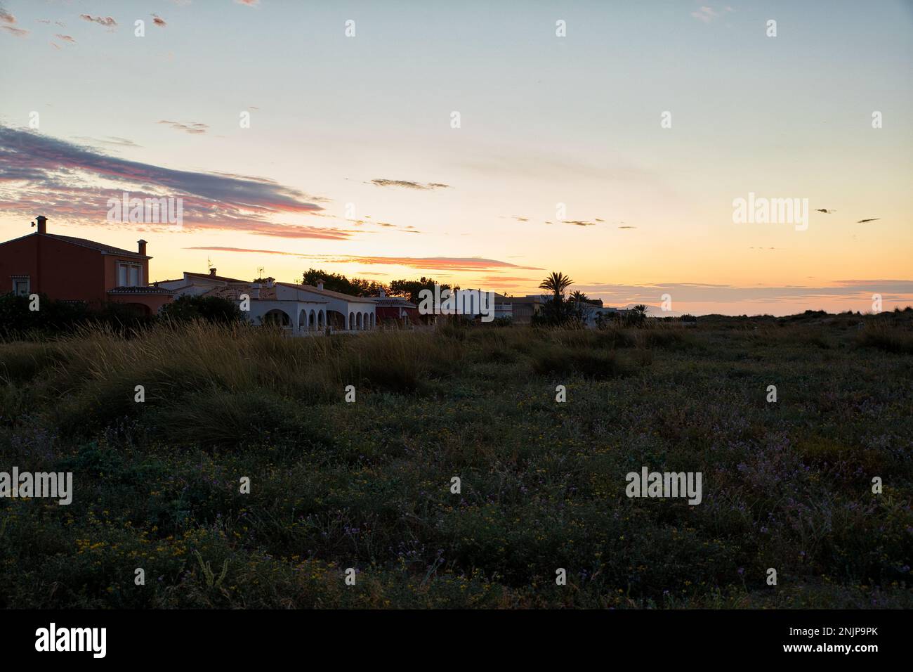 Sunset in a green landscape behind Spanish houses, the sky shines in ...