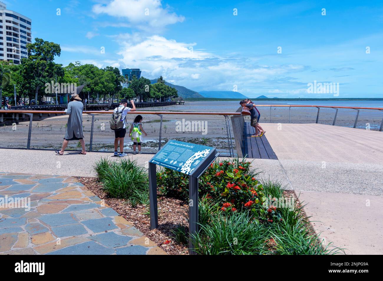 Tourists standing at the seafront along Cairns Esplanade on a sunny day ...