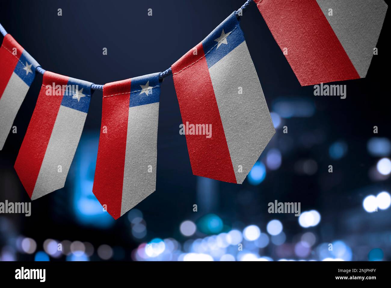 A garland of Chile national flags on an abstract blurred background ...