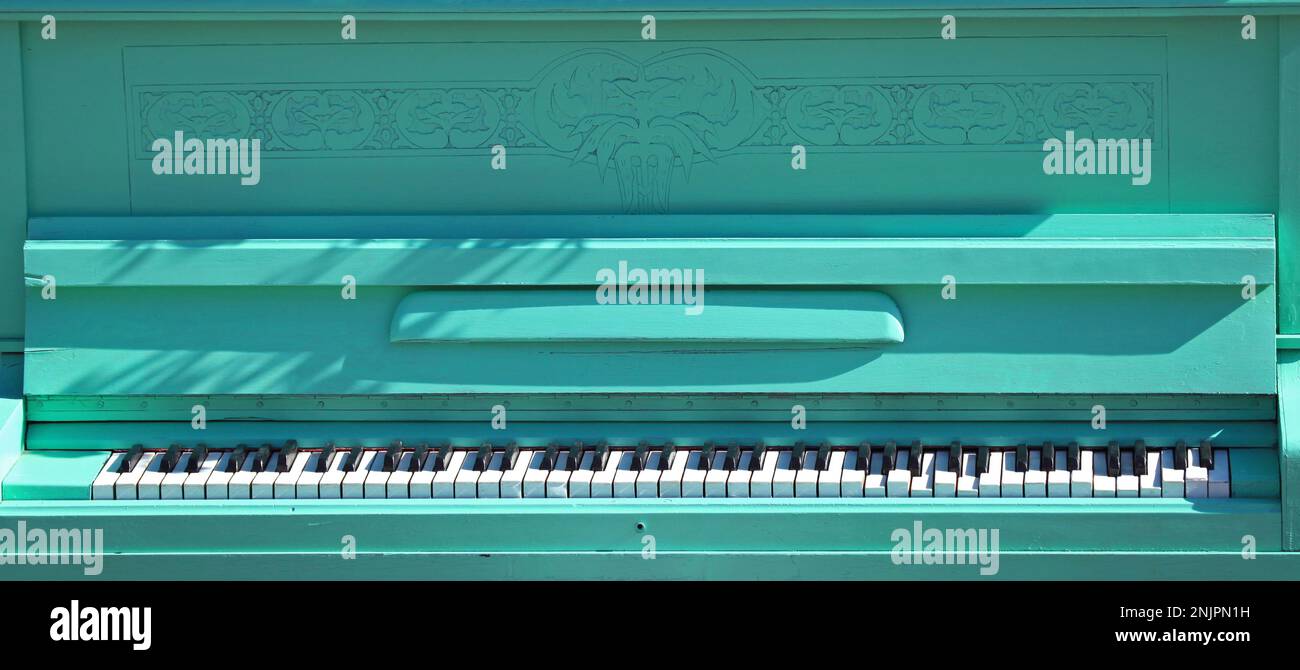 Fragment and exterior of light green piano in a city park in spring ...