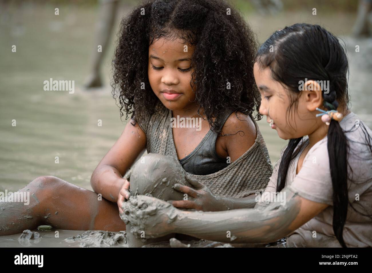 Group of happy children girl playing in wet mud puddle on summer day in ...