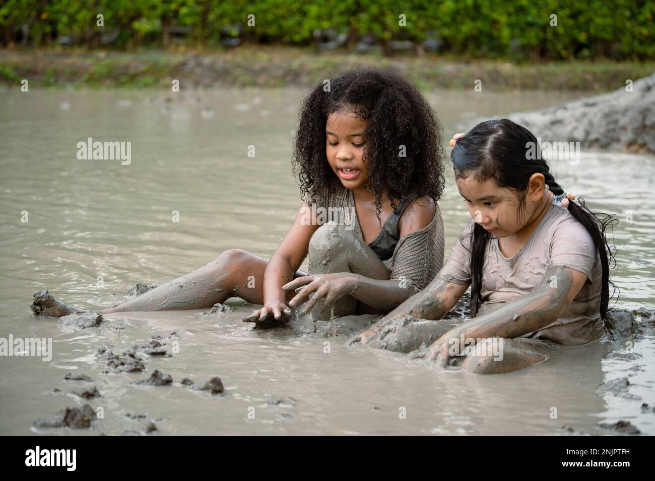 Group of happy children girl playing in wet mud puddle on summer day in ...