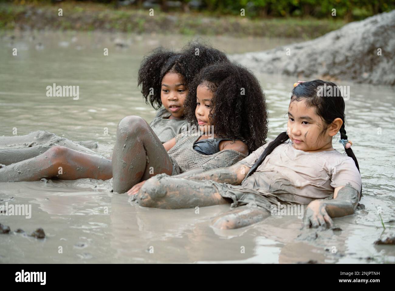 Group of happy children girl playing in wet mud puddle on summer day in ...