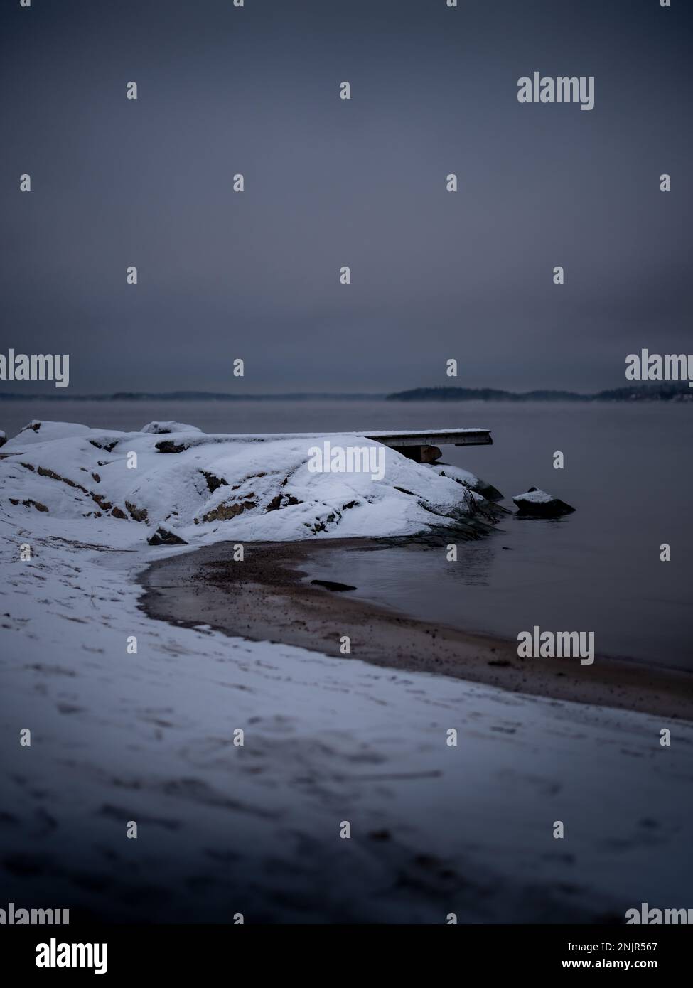 A Beach blanketed in the snow beside the ocean shoreline Stock Photo ...