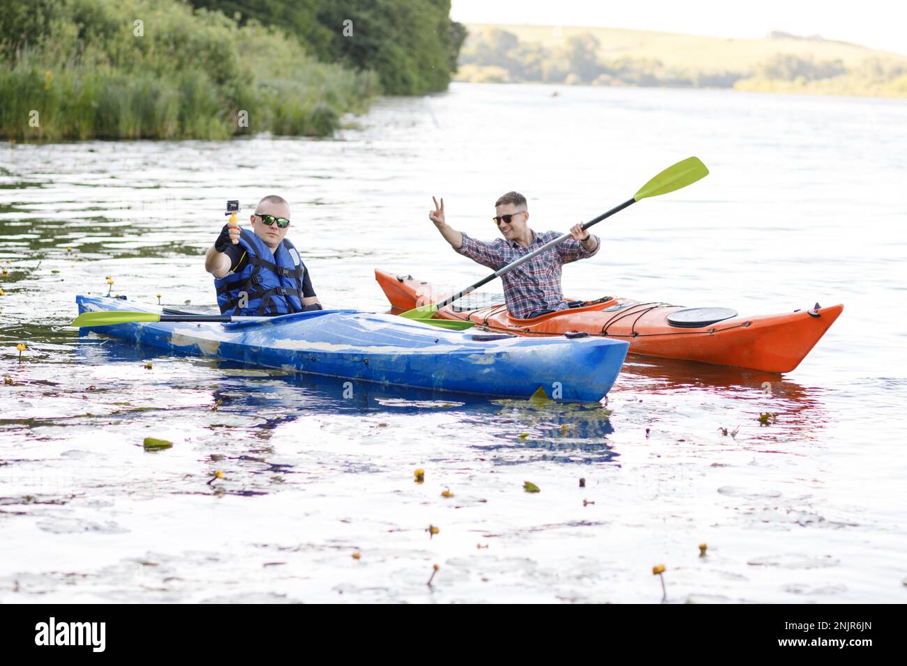 Kayaking on the river. Two young men sit in kayaks and take a selfie ...